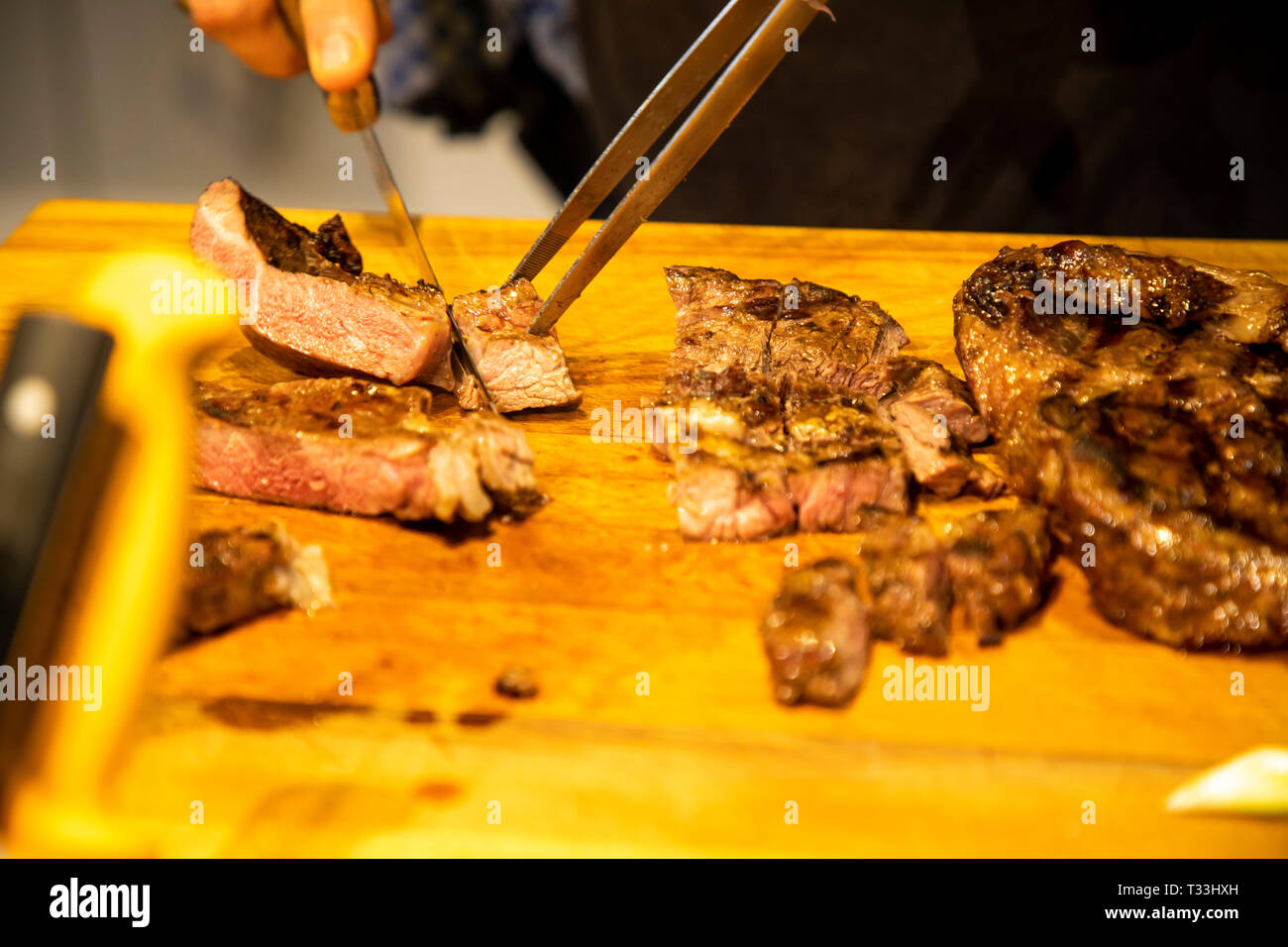 Grilled meat, beef, is cut portion by portion by the cook Stock Photo ...