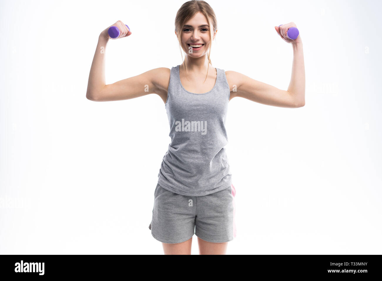 Portrait of pretty sporty girl holding weights dumbbells and make ...
