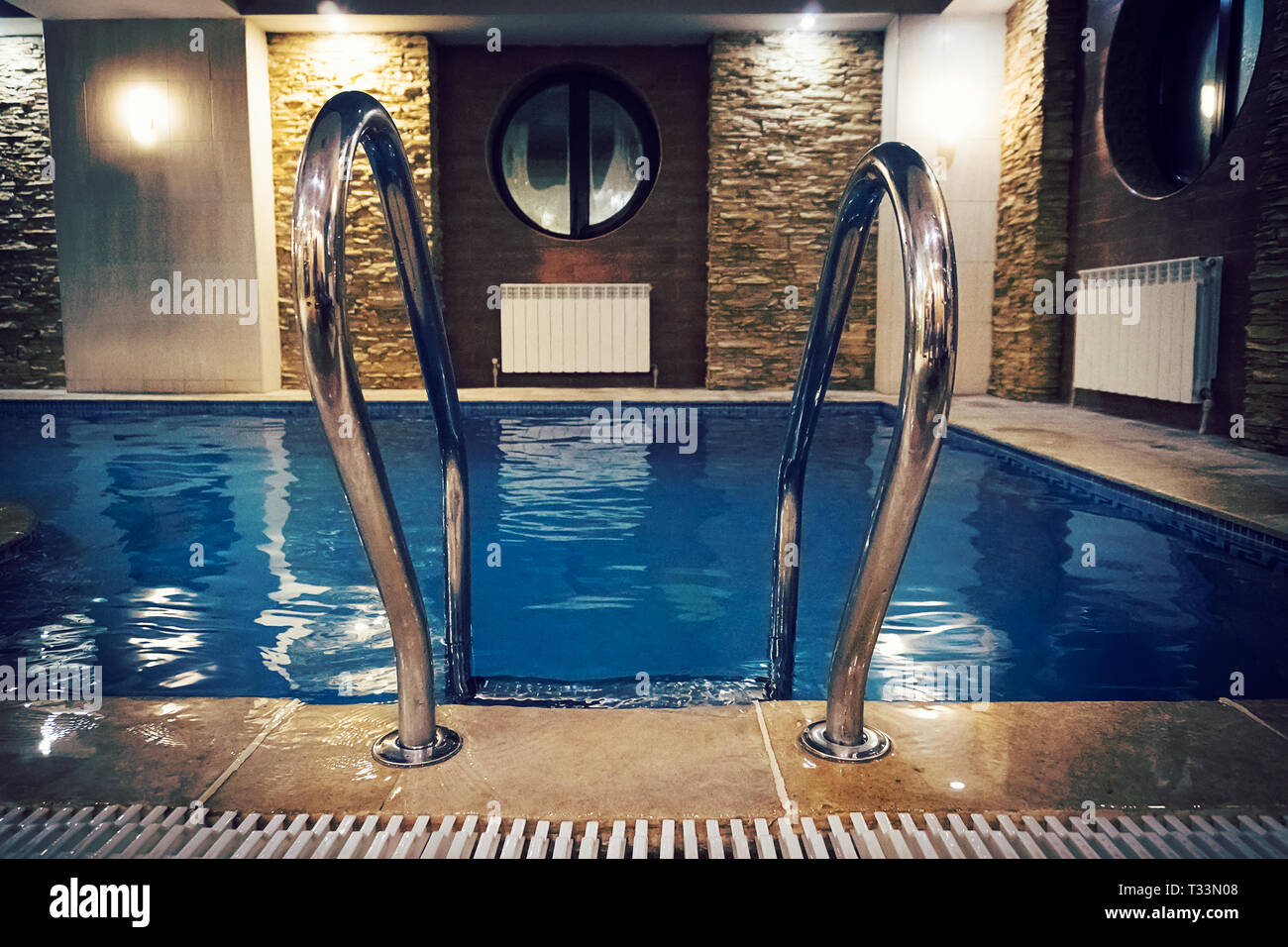 Grab bars ladder in the blue swimming pool. An indoor pool, indoors. A ...