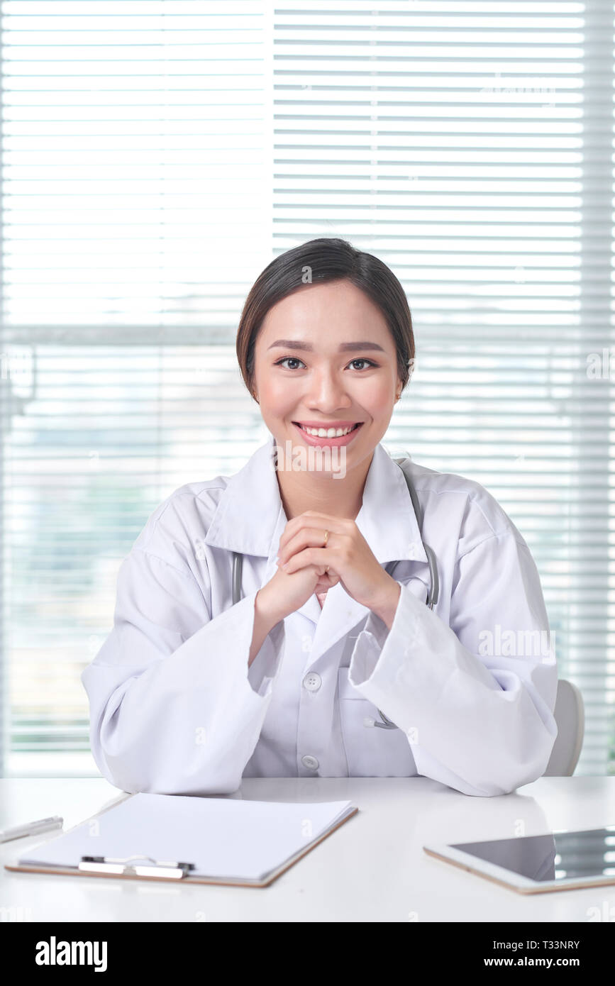 Female doctor working at office desk and smiling at camera Stock Photo ...