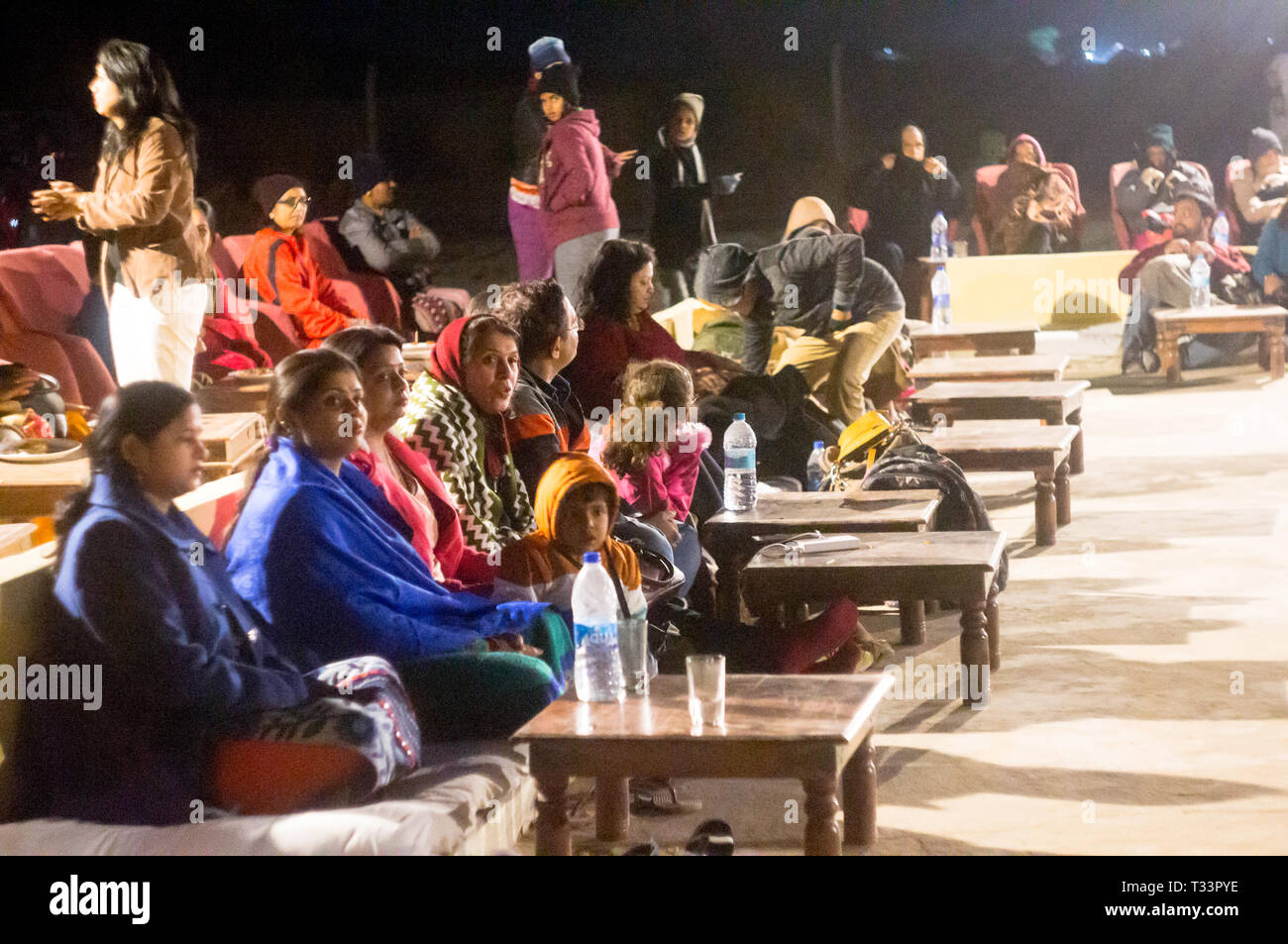 People sitting on low stools watching rajasthani entertainers at ...