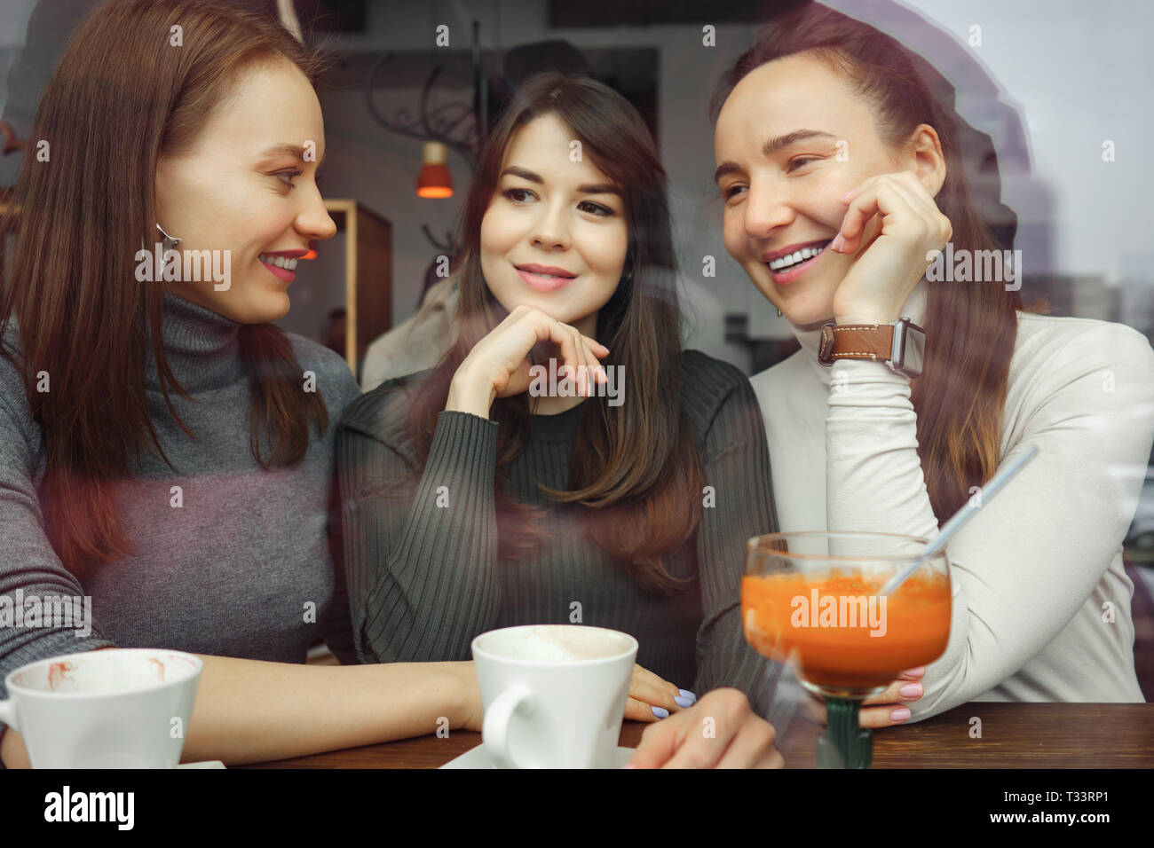 Women girlfriends in a cafe are having a fun chatting and drinking ...