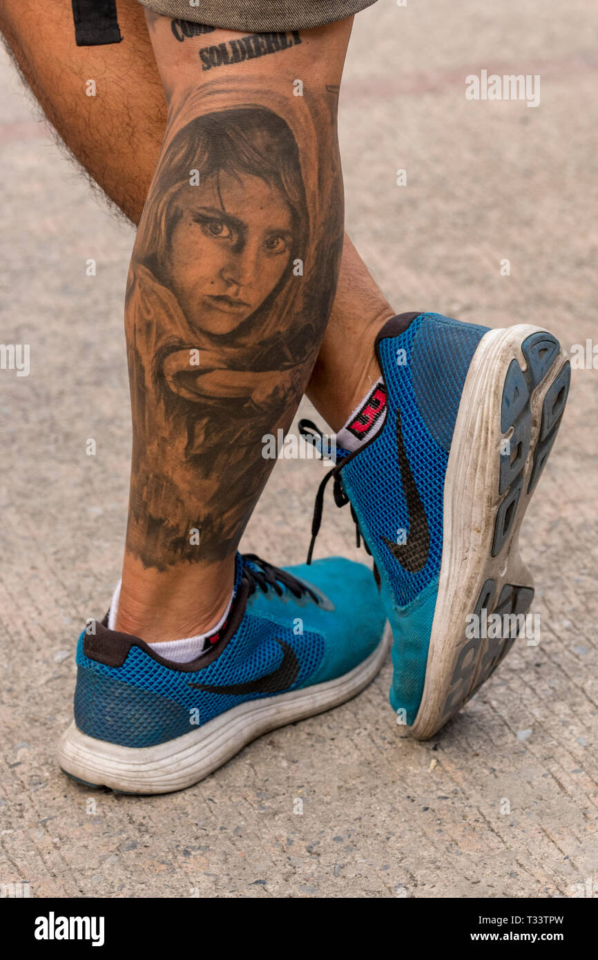 a large tattoo of a female face on the back of a mans leg or calf in ...