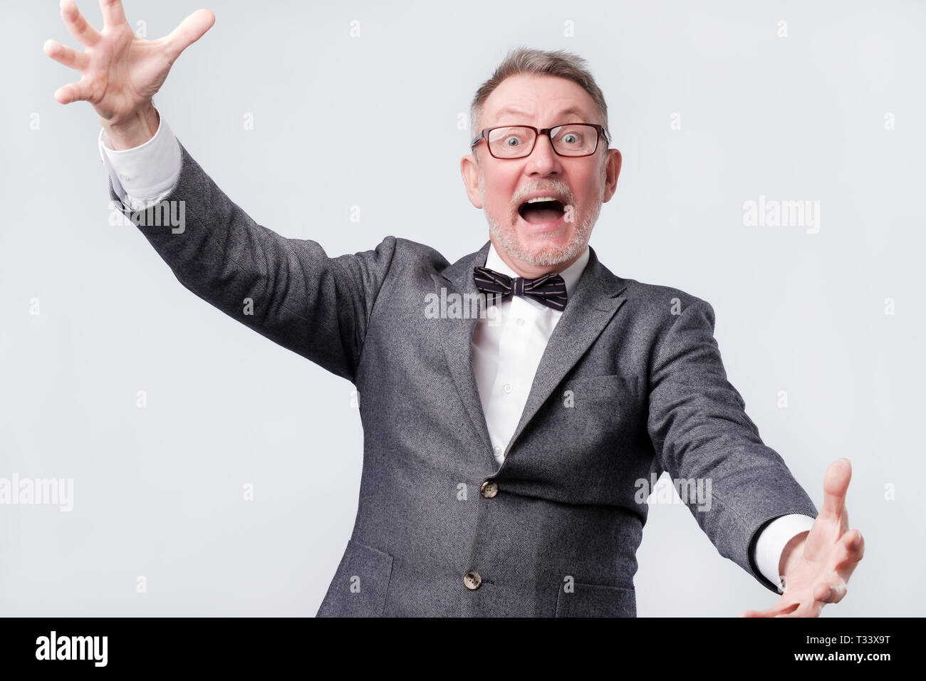 Senior man in suit joyfully stretches hands forward on a white ...