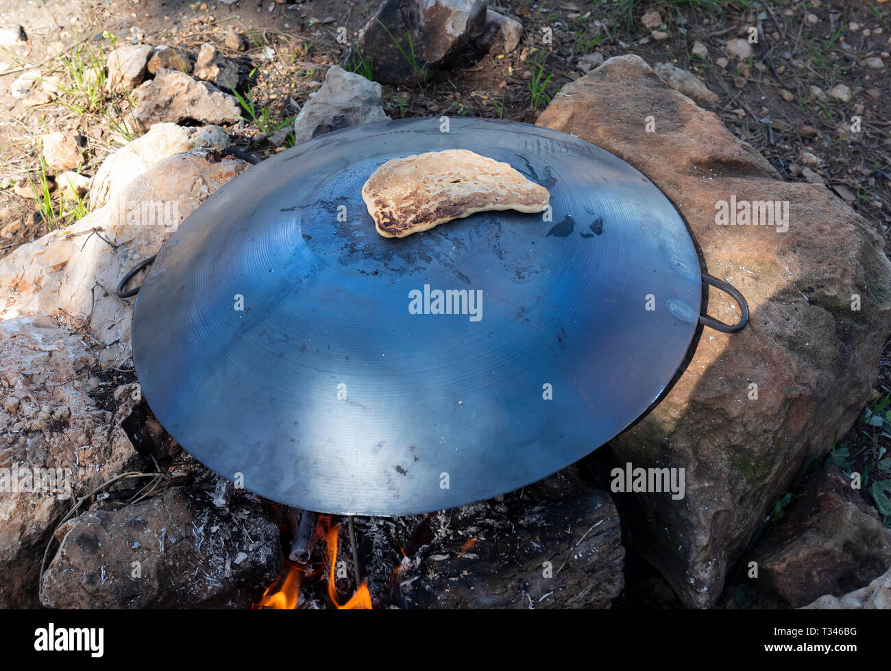 A pita bread being baked on a tava over a camp fire Stock Photo - Alamy