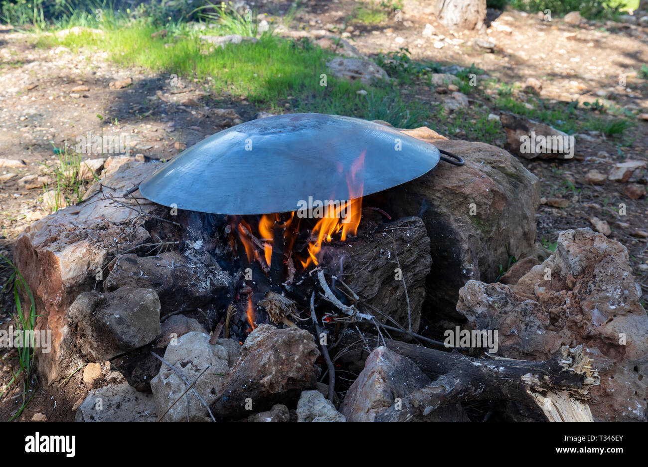 A tava, a concave metal baking instrument, heated over a campfire Stock ...