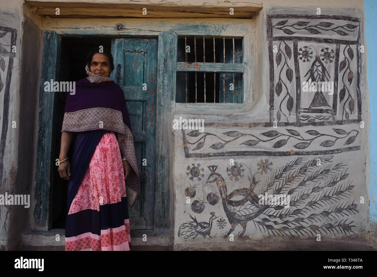 Low caste woman standing in front of her house decorated with mural ...