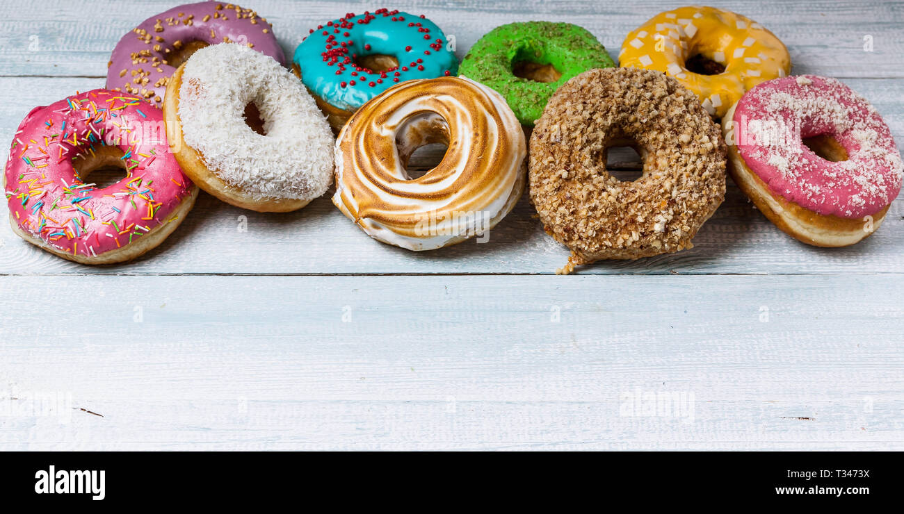 Food banner. Colorful donuts on a wooden table Stock Photo - Alamy