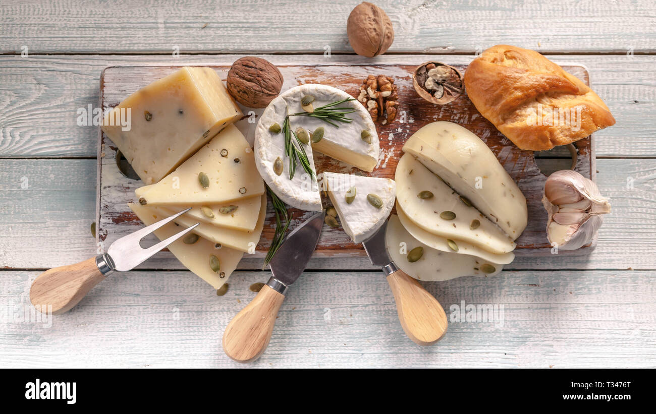 Food banner assorted fresh cheeses on a wooden board on wood background ...