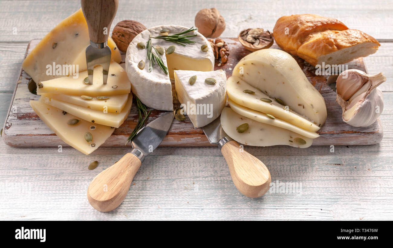Food banner assorted fresh cheeses on a wooden board on wood background ...