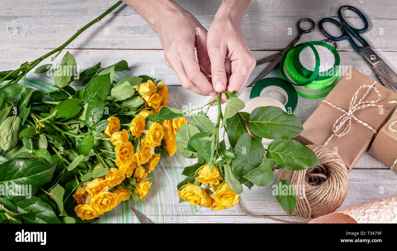 Florist at work. Female hands collect a wedding bouquet of roses ...