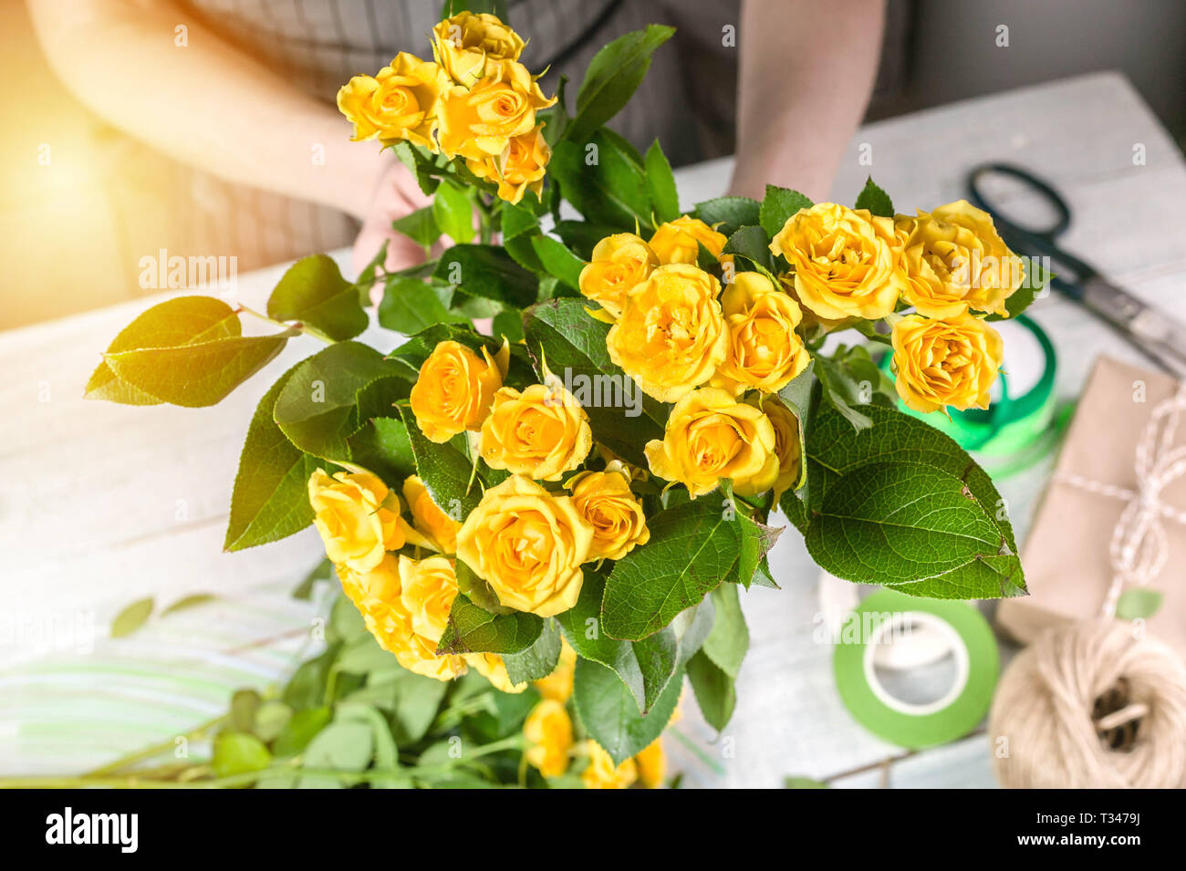 Florist at work. Female hands collect a wedding bouquet of roses ...