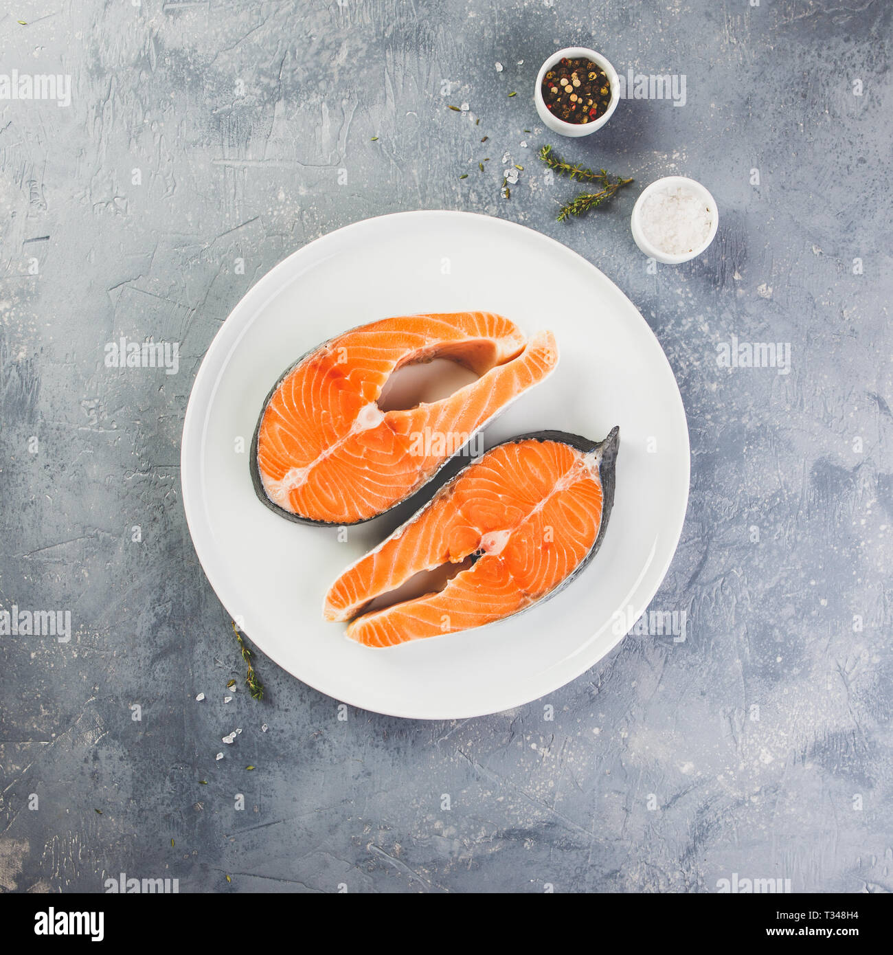 Two fresh raw salmon steaks with salt, peppers, on the rustic table ...