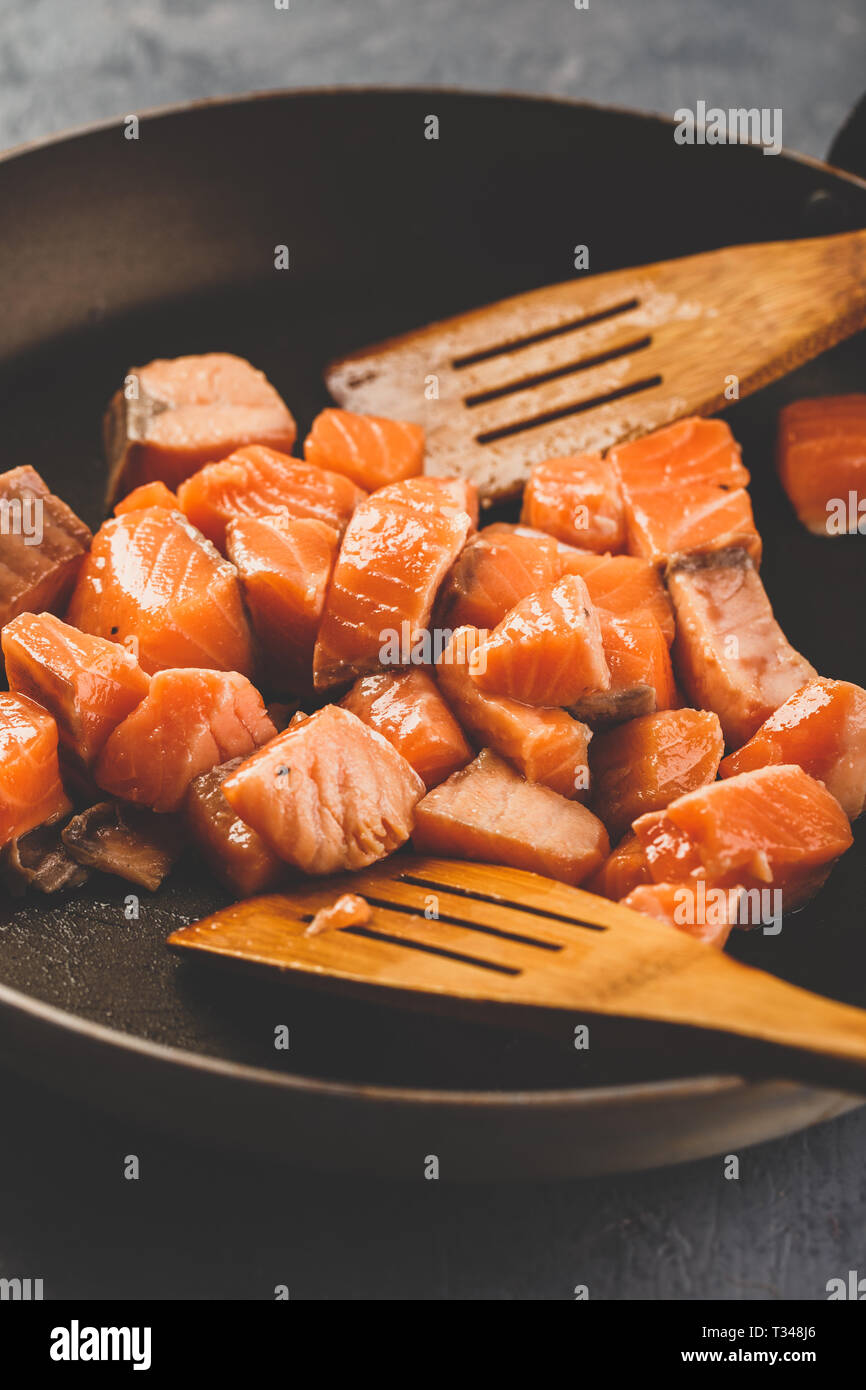 Diced salmon slices are fried in frying pan for pasta with creamy ...