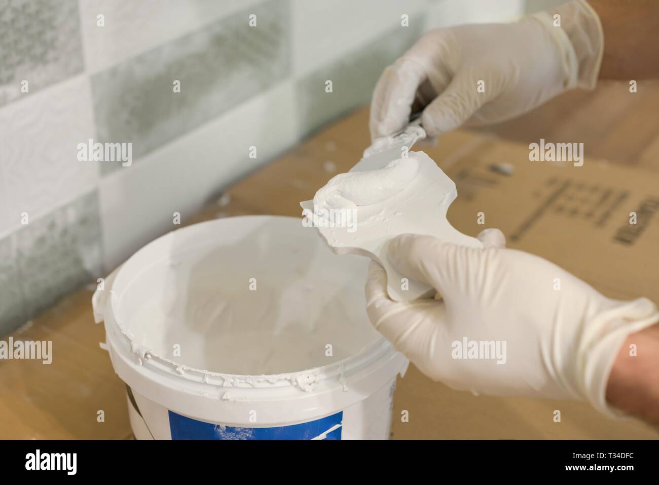 Final finishing work with laying of ceramic tiles. Close-up of hands ...