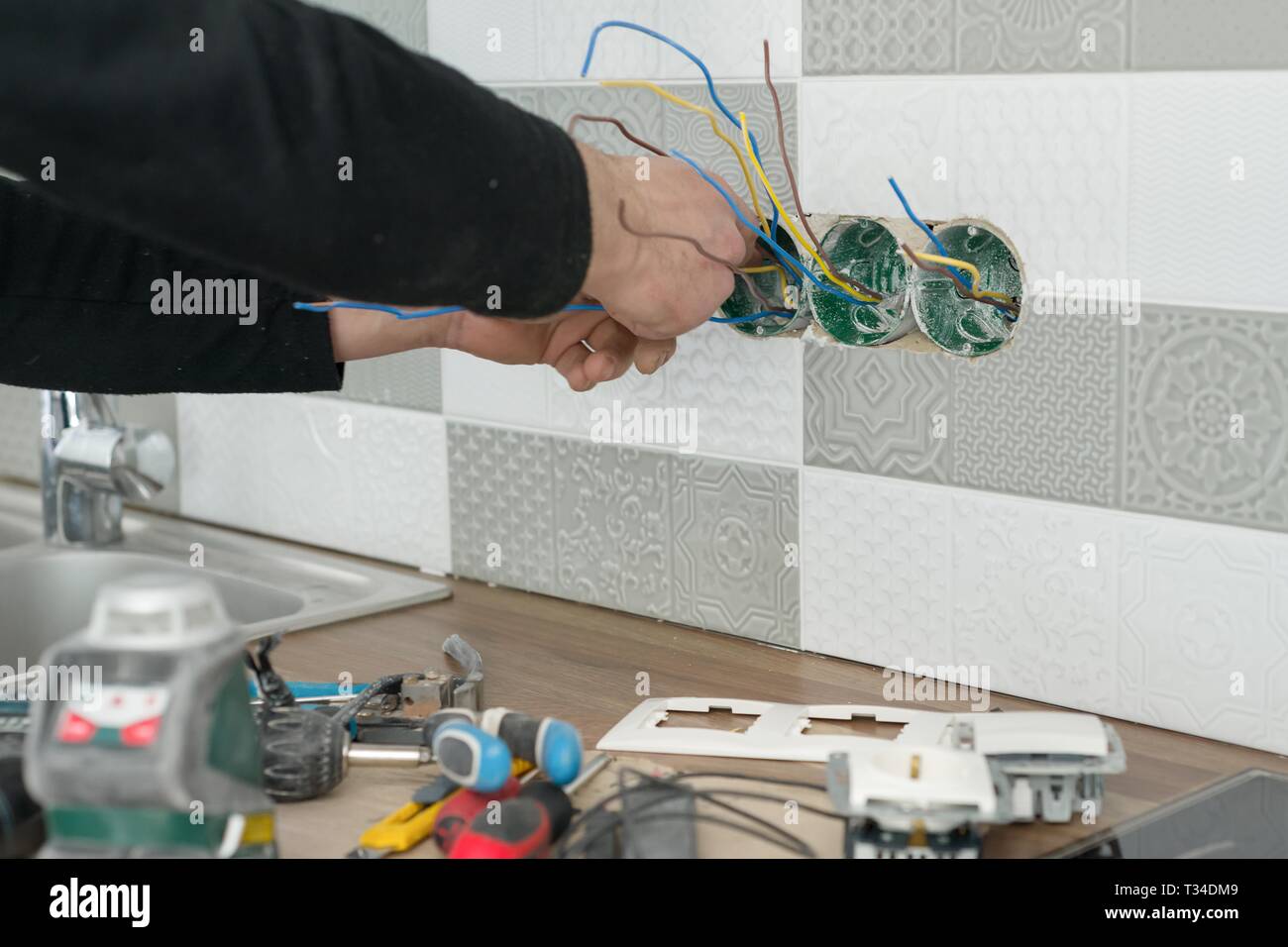 Renovation and construction in kitchen, close-up of electricians hand ...