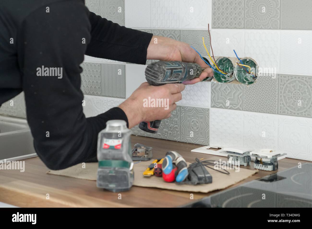 Renovation and construction in kitchen, close-up of electricians hand ...