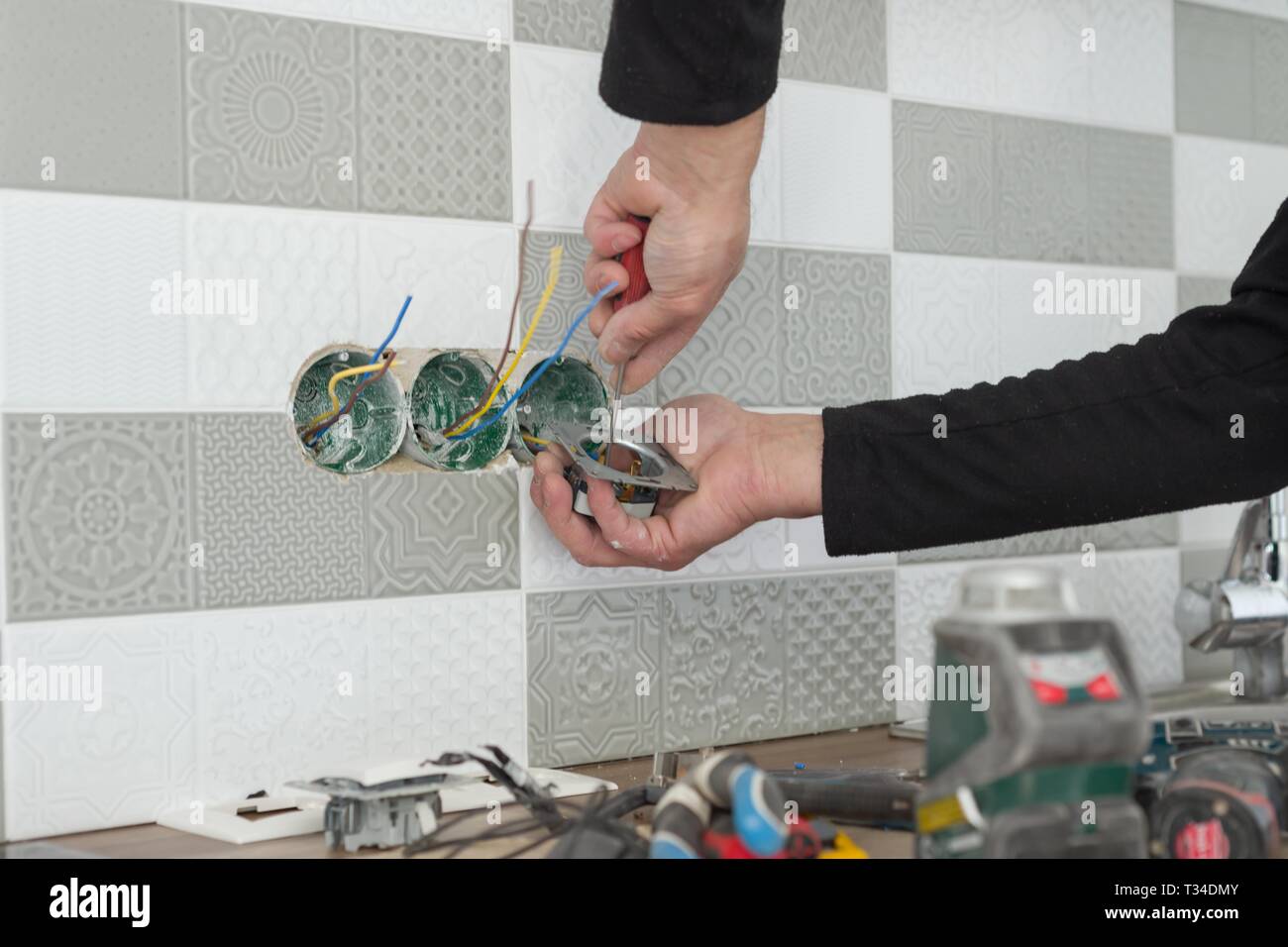 Renovation and construction in kitchen, close-up of electricians hand ...