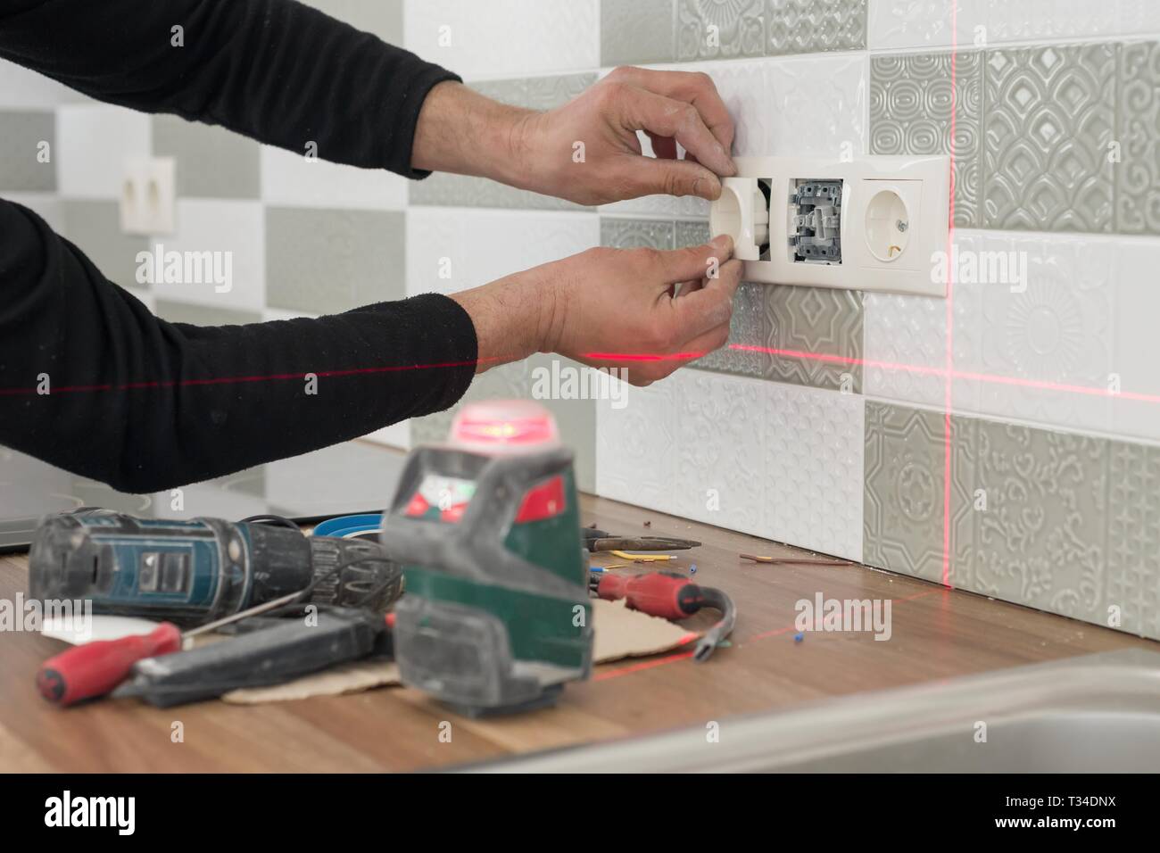 Electrician using infrared laser level to install electrical outlets ...