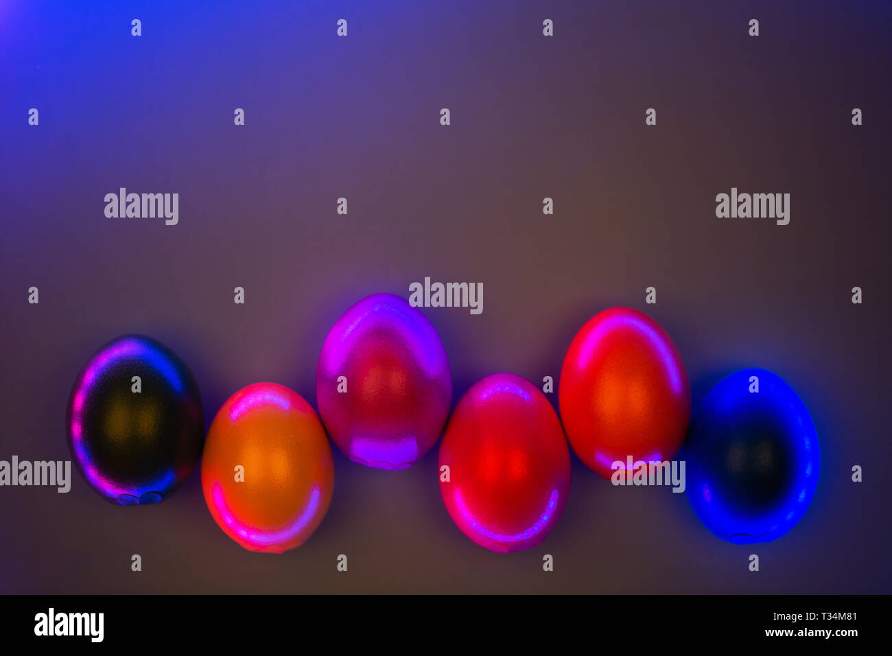 Creative photo of colorful eggs in neon lights on grey background ...