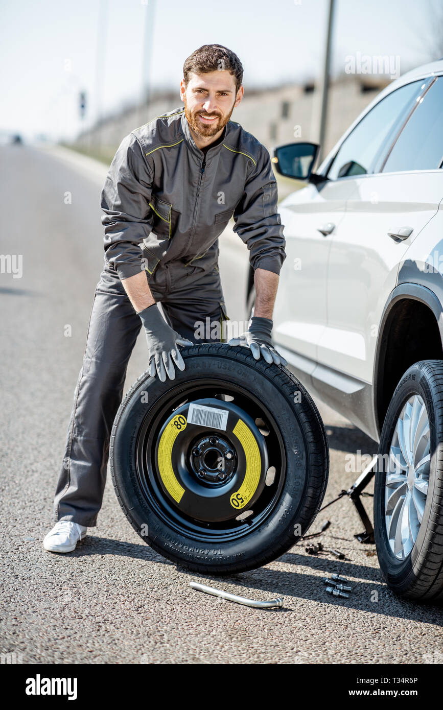 Portrait of a handsome road assistance worker in uniform standing with ...