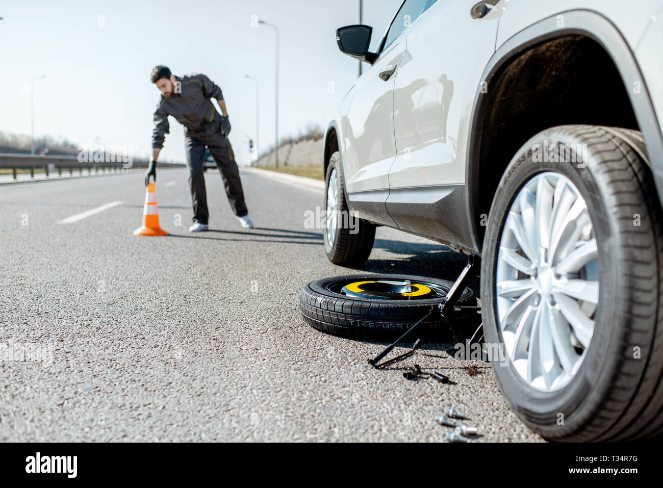 Road assistance worker putting emergency cones near the broken car on ...