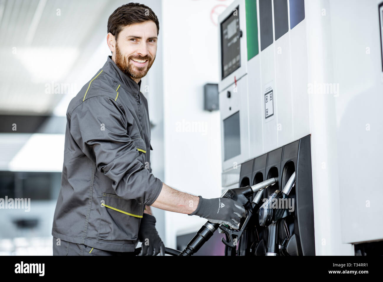 Gas station worker in uniform taking filling gun, refueling car at the ...