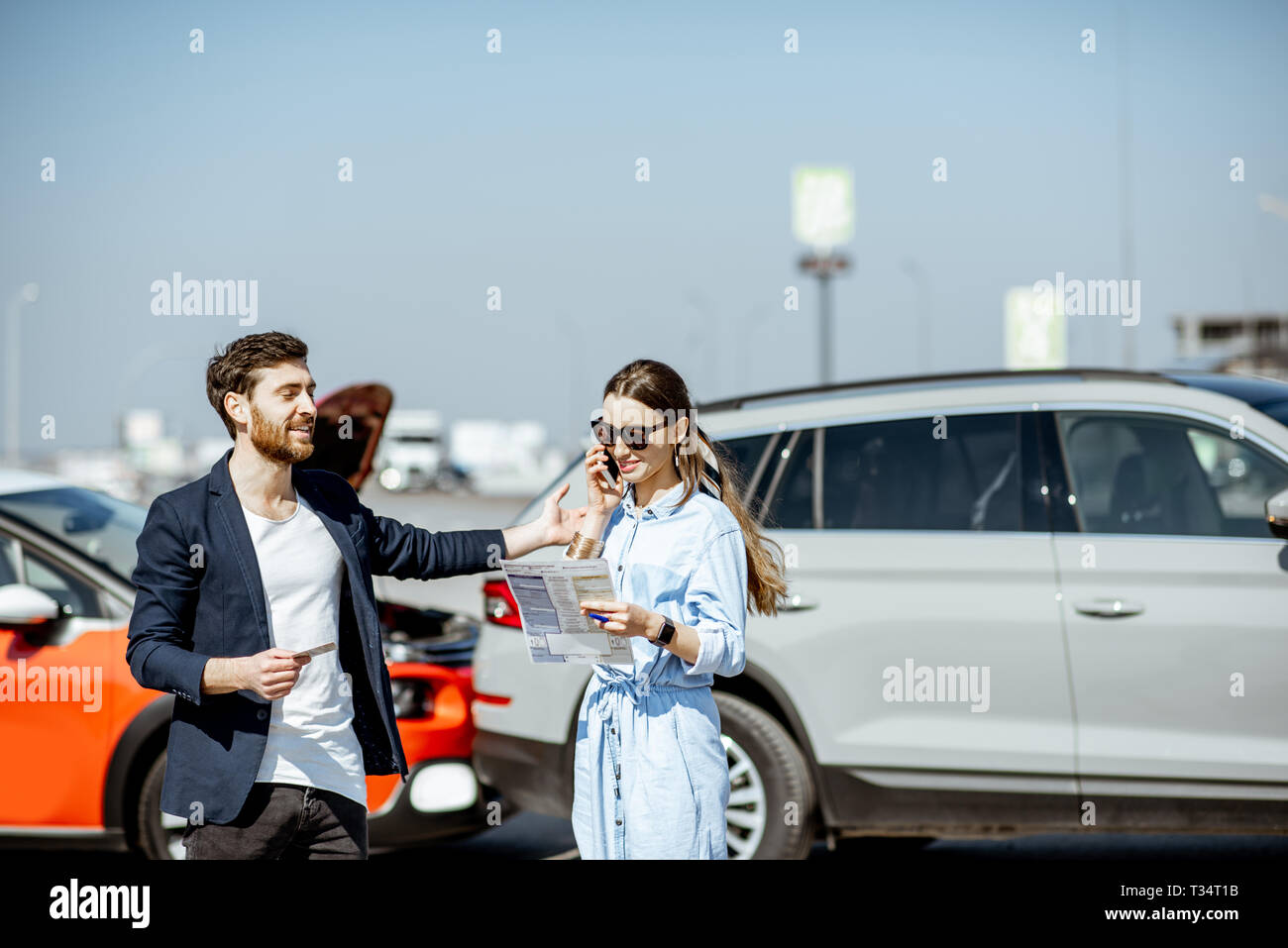 Man and woman arguing, standing together on the road with their cars on ...