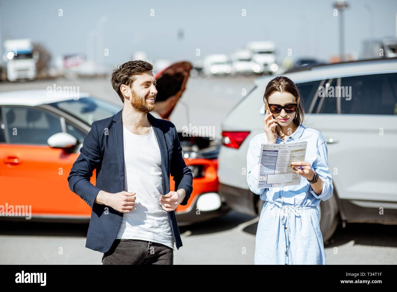Man and woman arguing, standing together on the road with their cars on ...