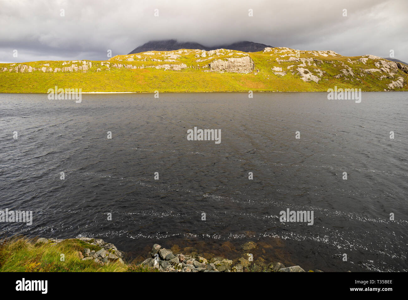 Sun illuminates the northern shore of Loch Stack with Ben Arkle in the ...