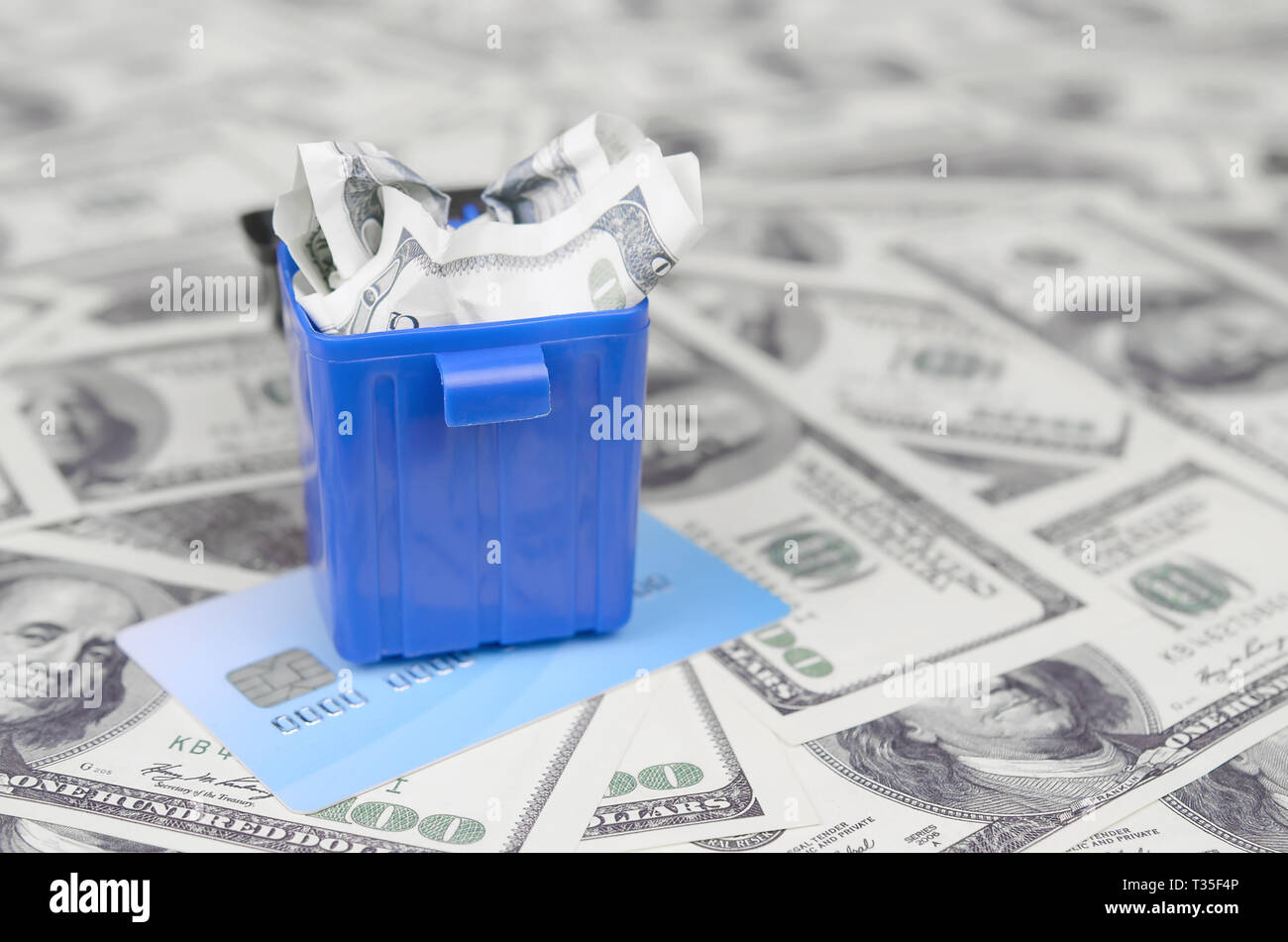 Dollar bills thrown into the trash and bank card. The concept of ...