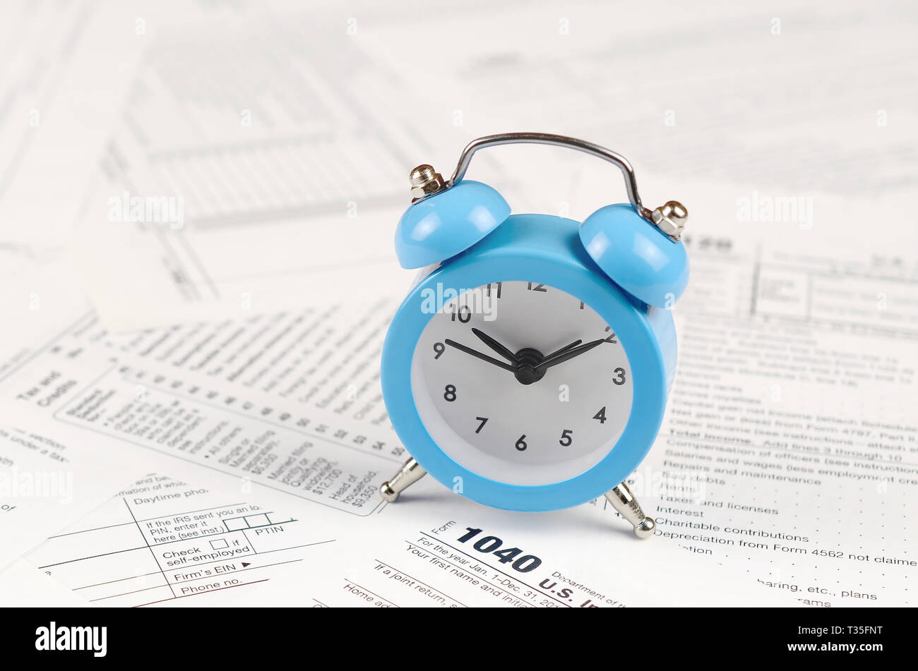 1040 Individual income tax return form with blue alarm clock. Concept ...