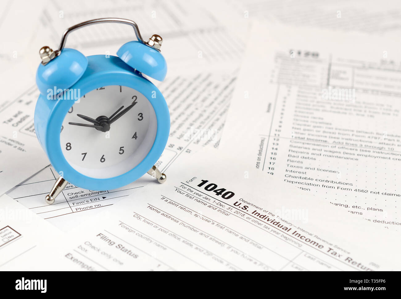 1040 Individual income tax return form with blue alarm clock. Concept ...