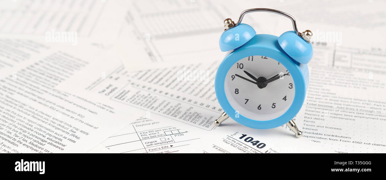 1040 Individual income tax return form with blue alarm clock. Concept ...