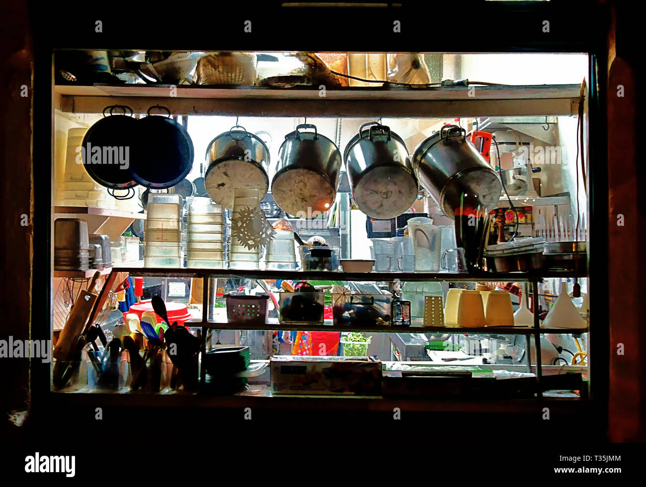 Pots and other chef tools hung and on a shelf in the window of a ...