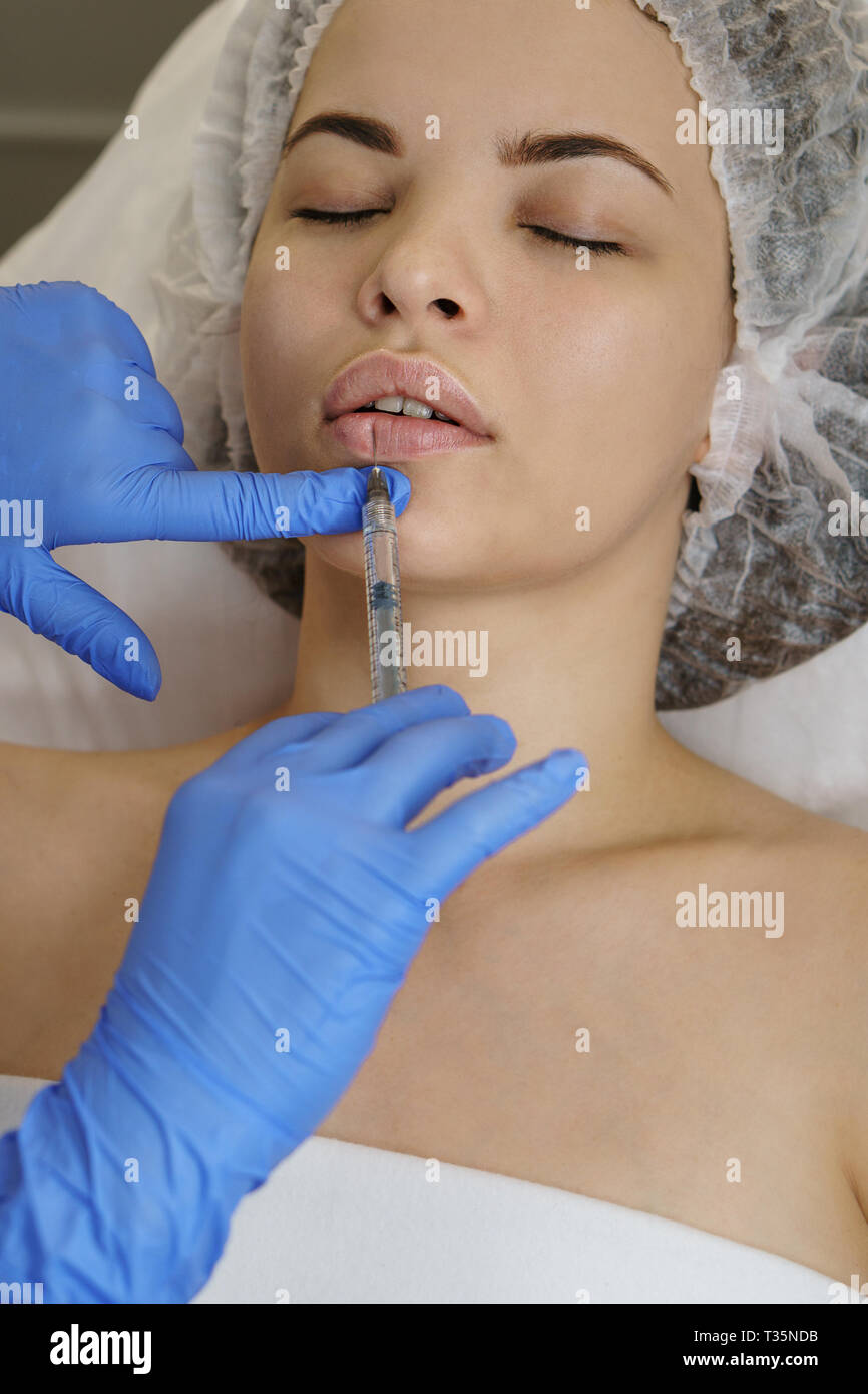 Aesthetic cosmetology. Lip augmentation in spa salon. Beautician makes ...