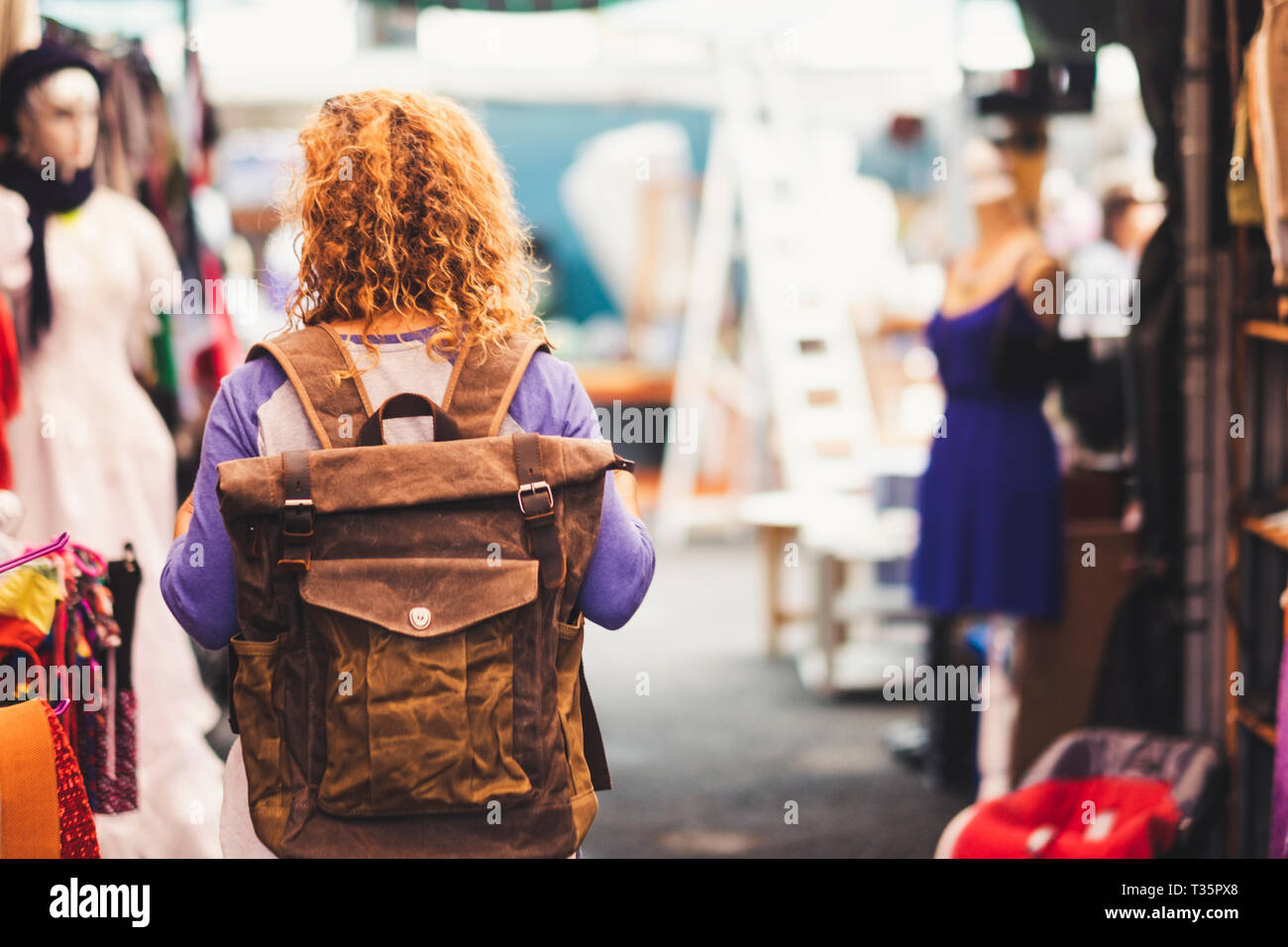 Blonde curly hair woman backpacker traveler viewed from rear at used ...