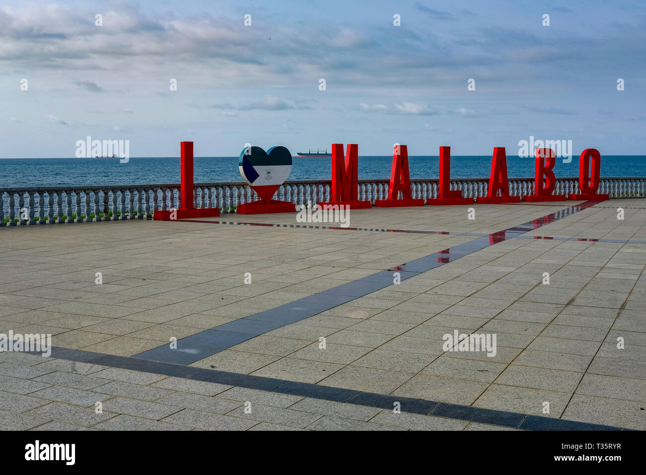 Letters reading "I love Malabo" in red on a walkway in front of the sea ...
