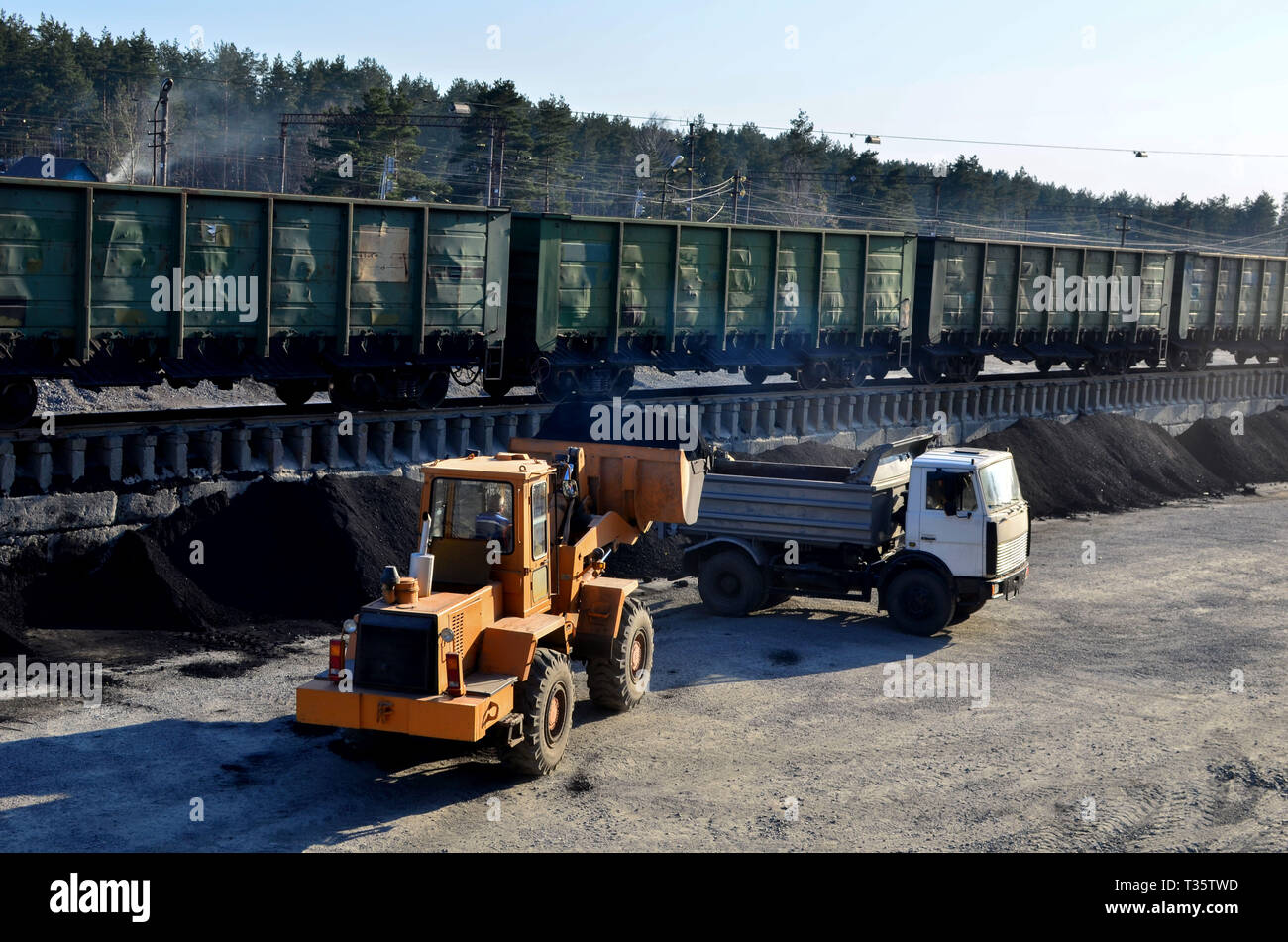 Wheel loader unloading coal into a heavy dump truck at a cargo railway ...