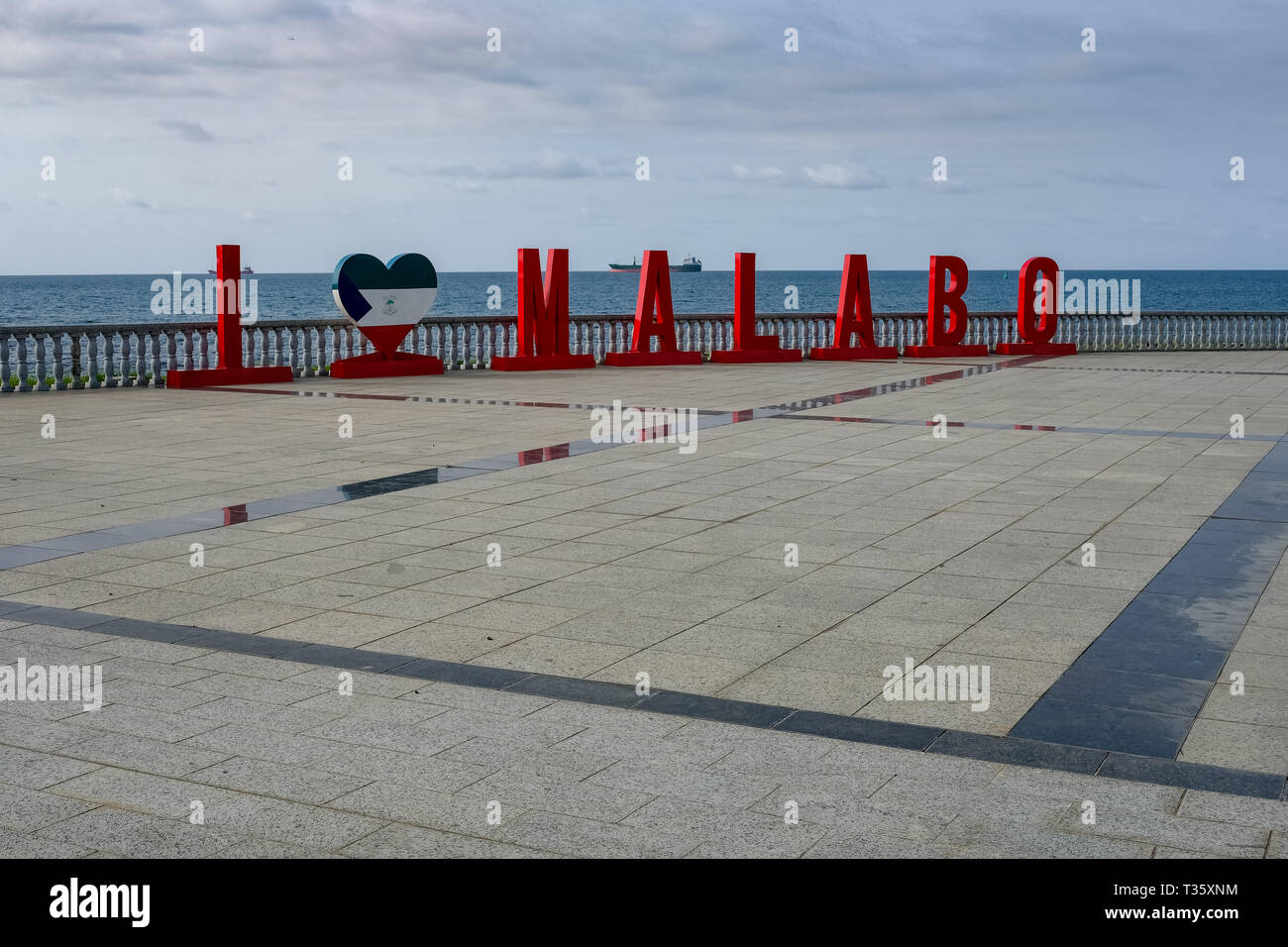 Letters reading "I love Malabo" in red on a walkway in front of the sea ...