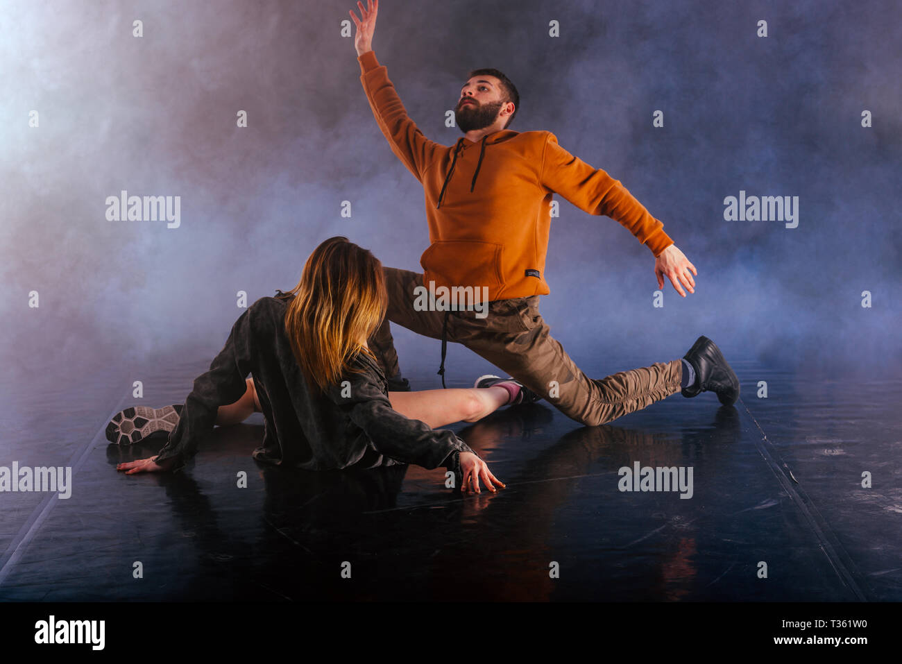 The beautiful female dancer is laying on the floor while her male ...