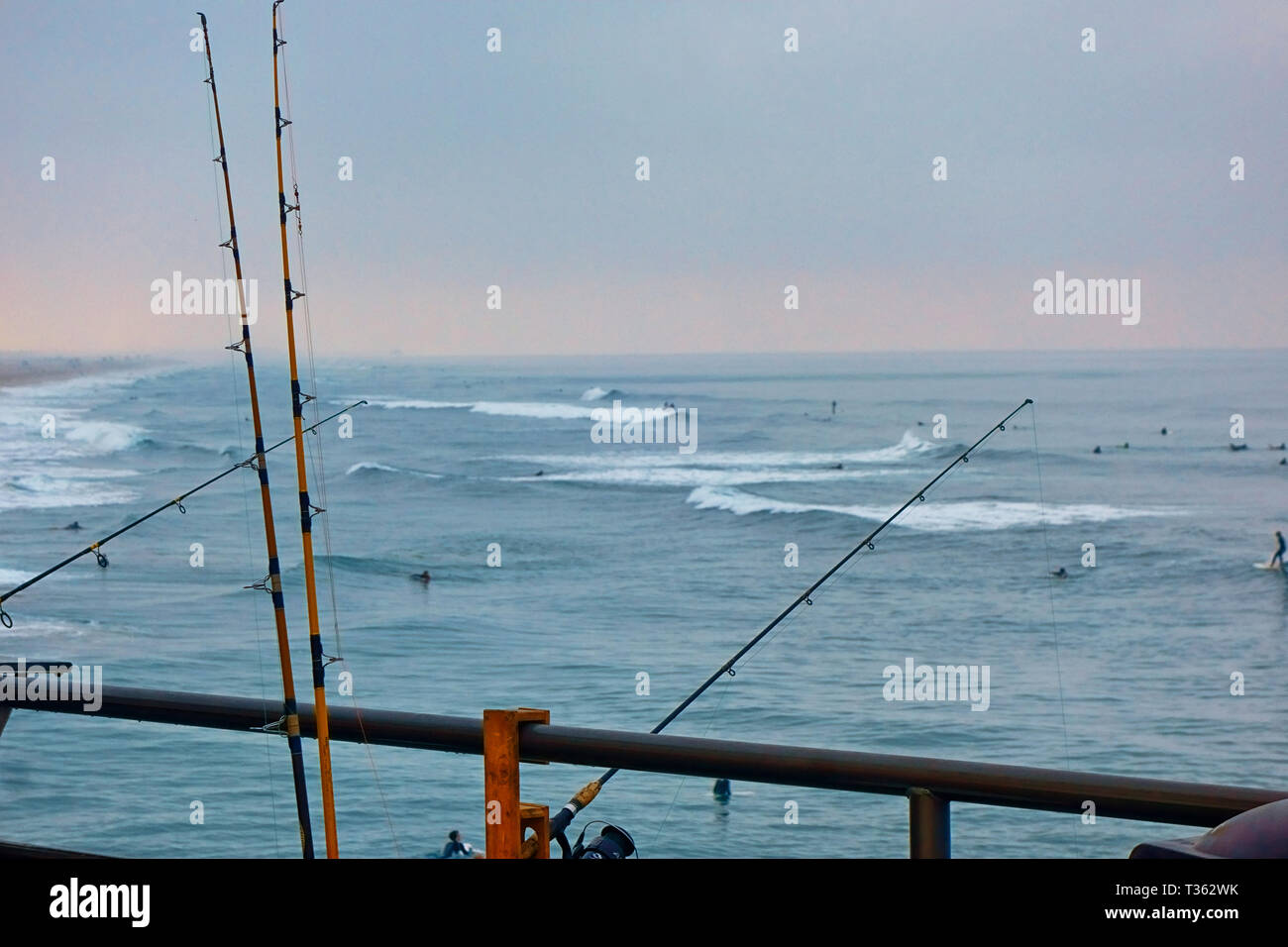 Fishing poles hanging over the railing at the Huntington Beach Pier ...