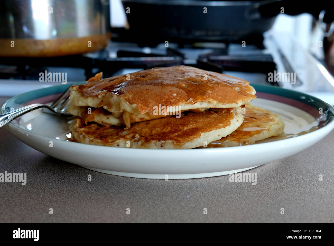Plate of rustic homemade pancakes with syrup on a plate on a kitchen ...