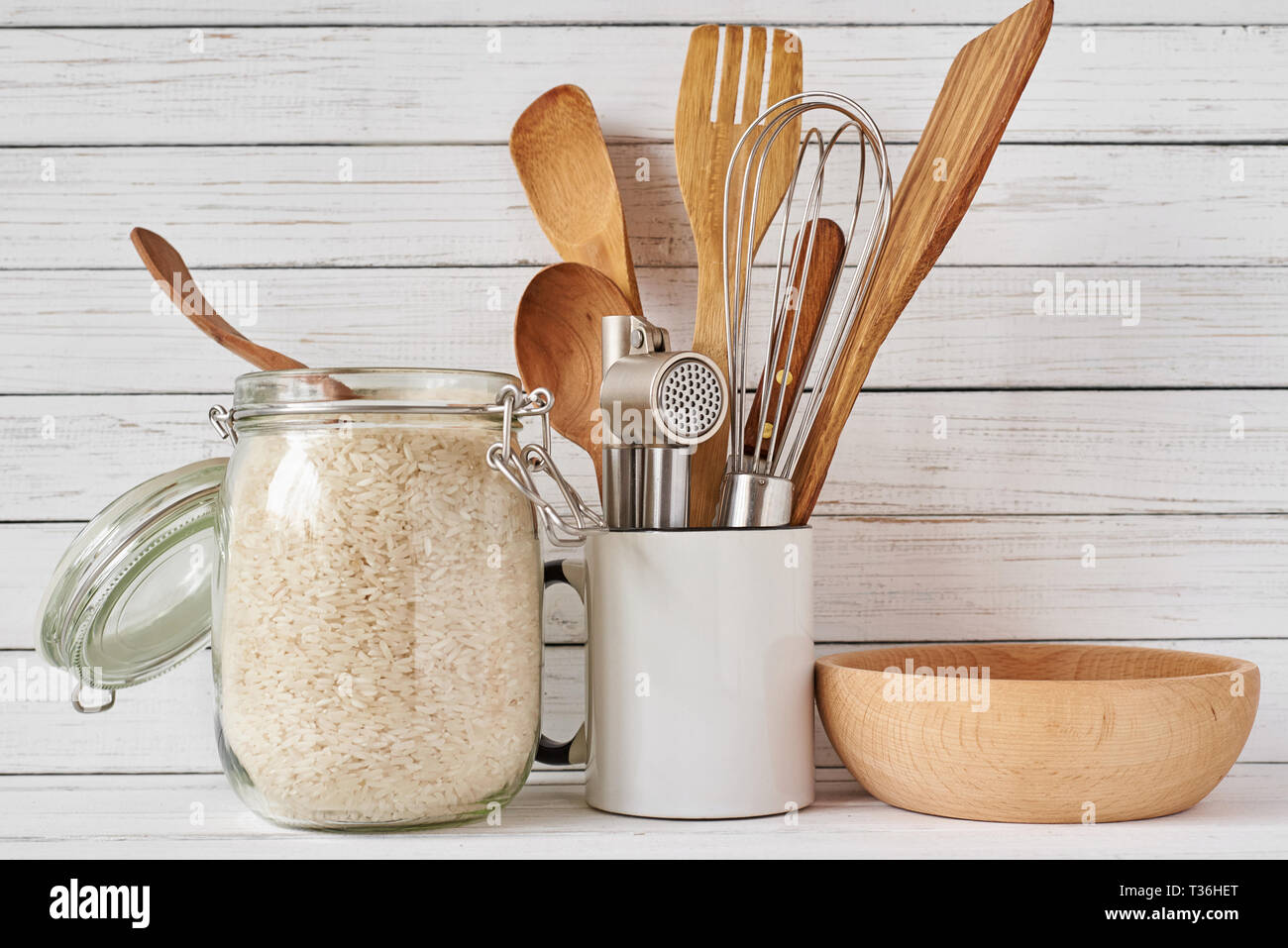 Kitchen tools and glass jar with rice on white table, front view ...