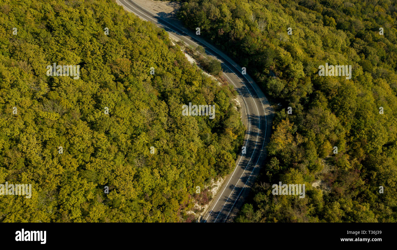 Aerial above view of a rural landscape with a curvy road running ...