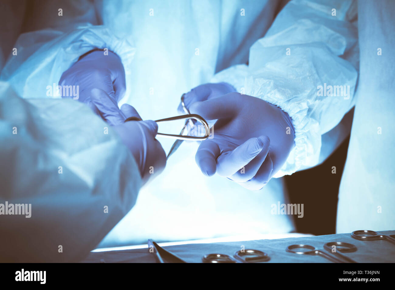 Surgeons hands holding surgical scissors and passing surgical equipment ...