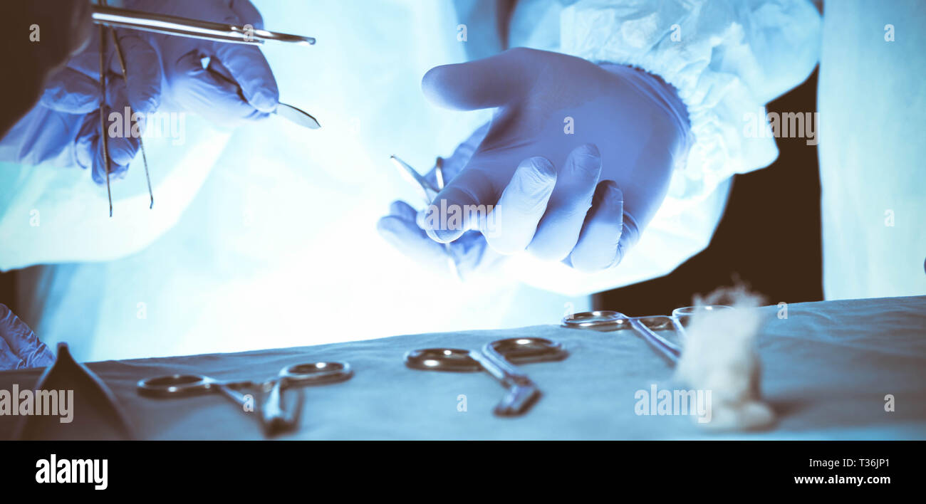 Surgeons hands holding surgical scissors and passing surgical equipment ...