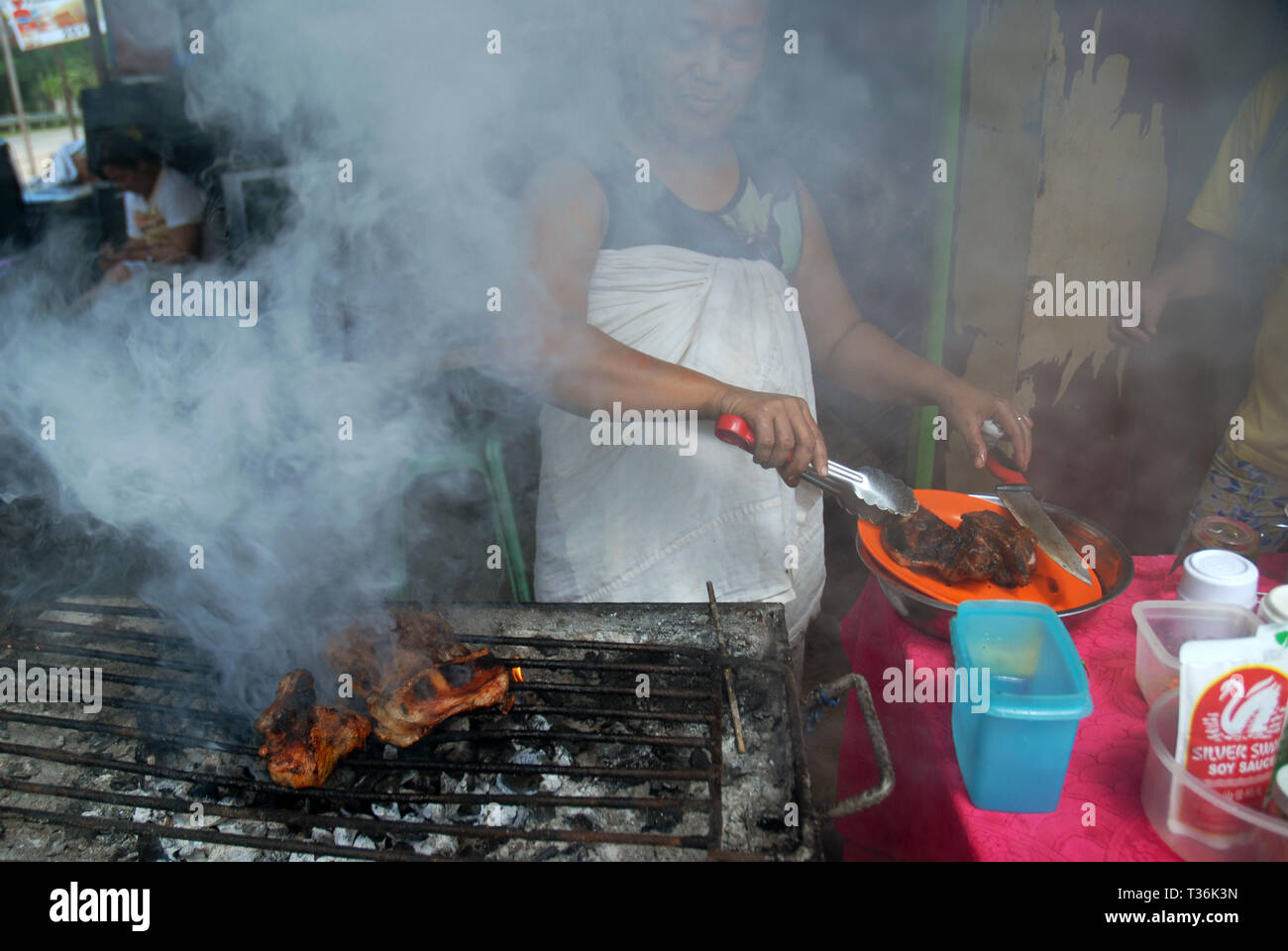 Lady cooking meat to sell at food stall, Samal, Philippines Stock Photo ...