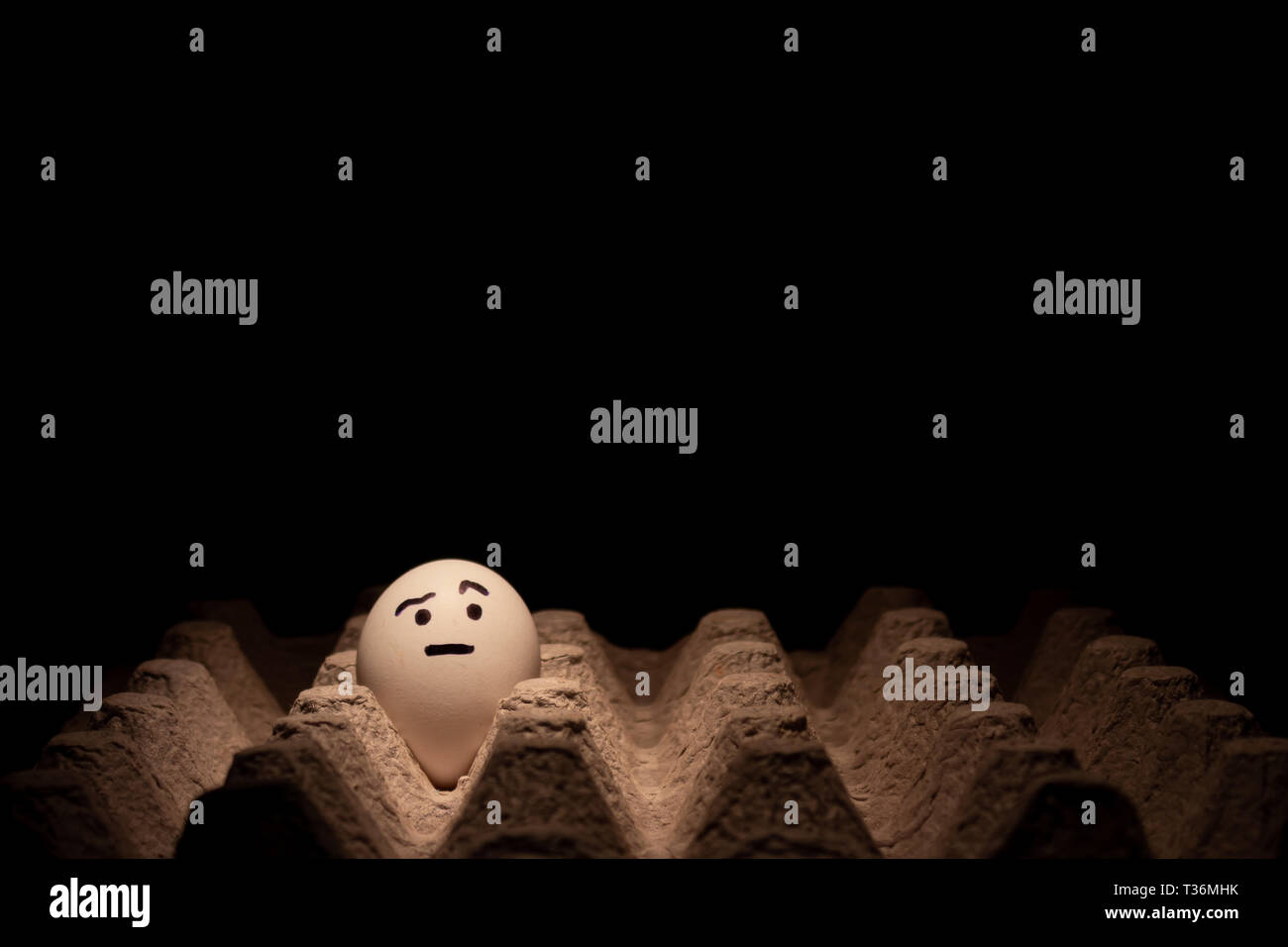 Egg with face on a carton and neutral background black. Conceptual ...