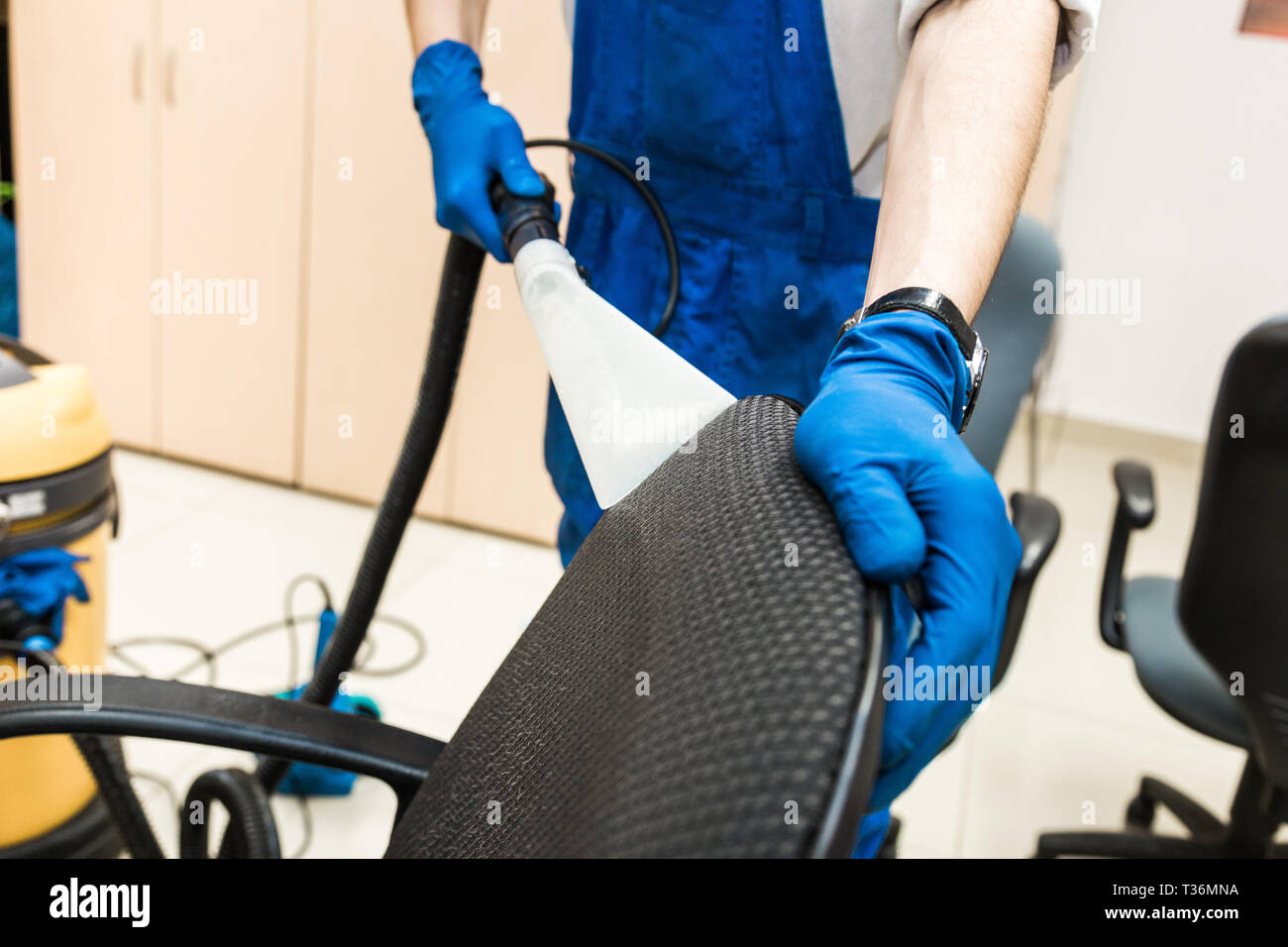 Cleaning service. Young man in workwear and rubber gloves cleans the ...